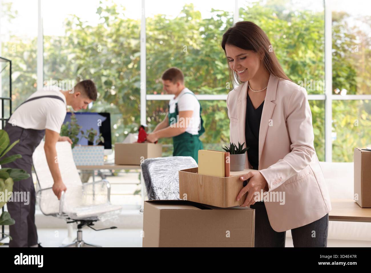 Moving day. Group of workers packing different belongings into boxes in ...