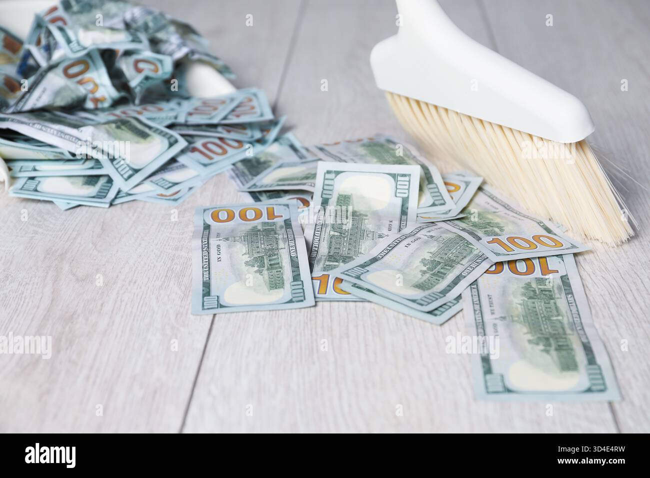 Sweeping dollar banknotes with broom on light wooden floor, closeup ...