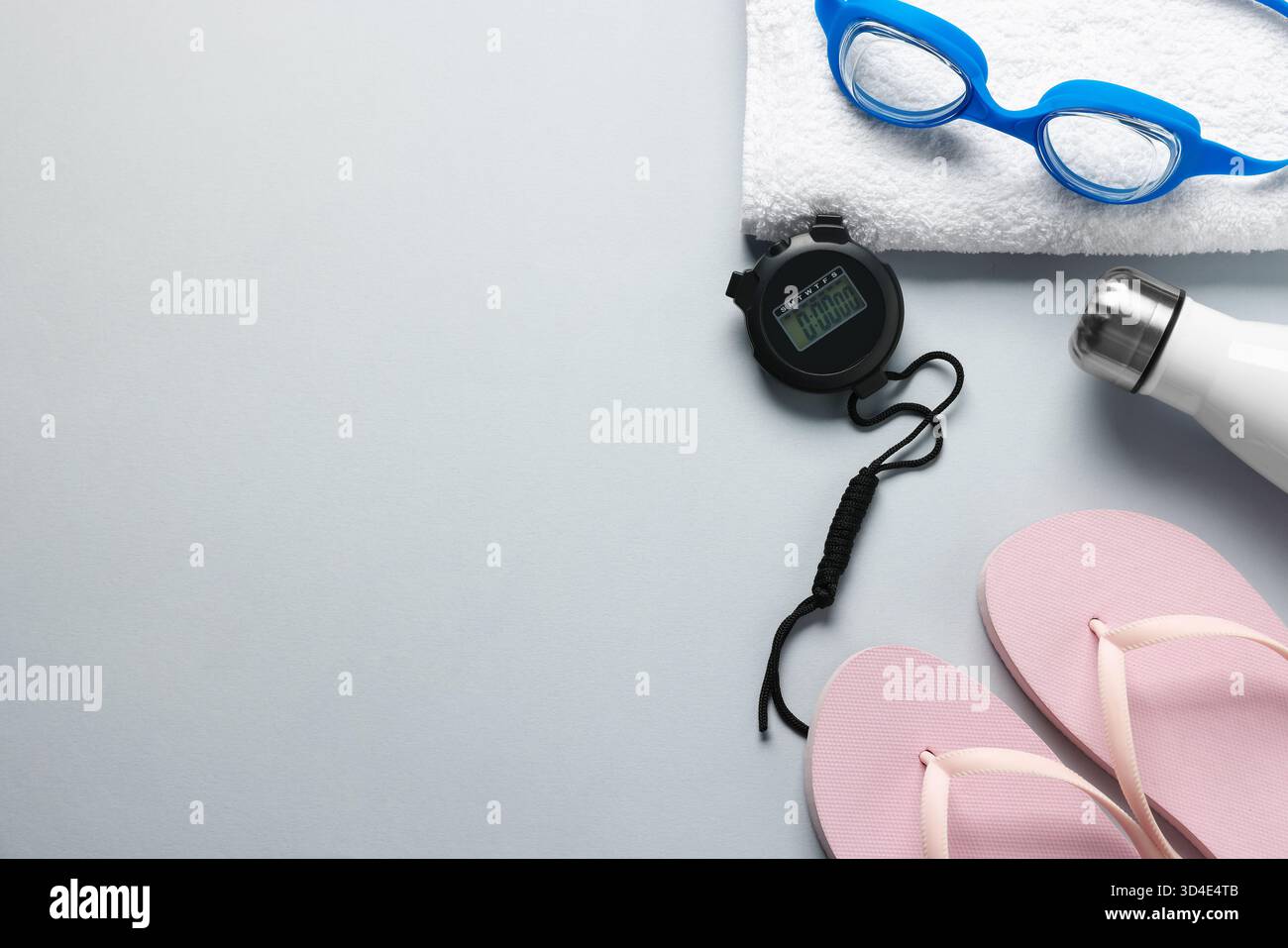 Flip flops, towel, goggles, bottle and digital stopwatch on light grey ...