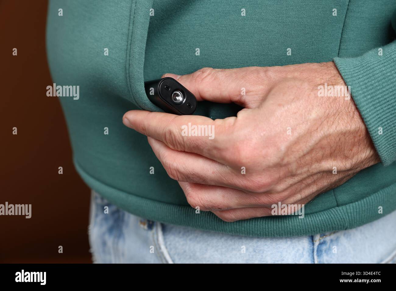 Man with hidden spy camera in his pocket on brown background, closeup ...