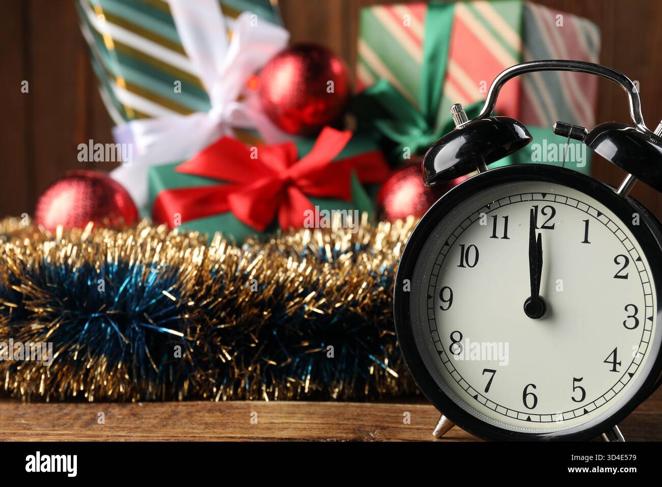 Alarm clock, tinsel, baubles and gift boxes on wooden table, closeup ...