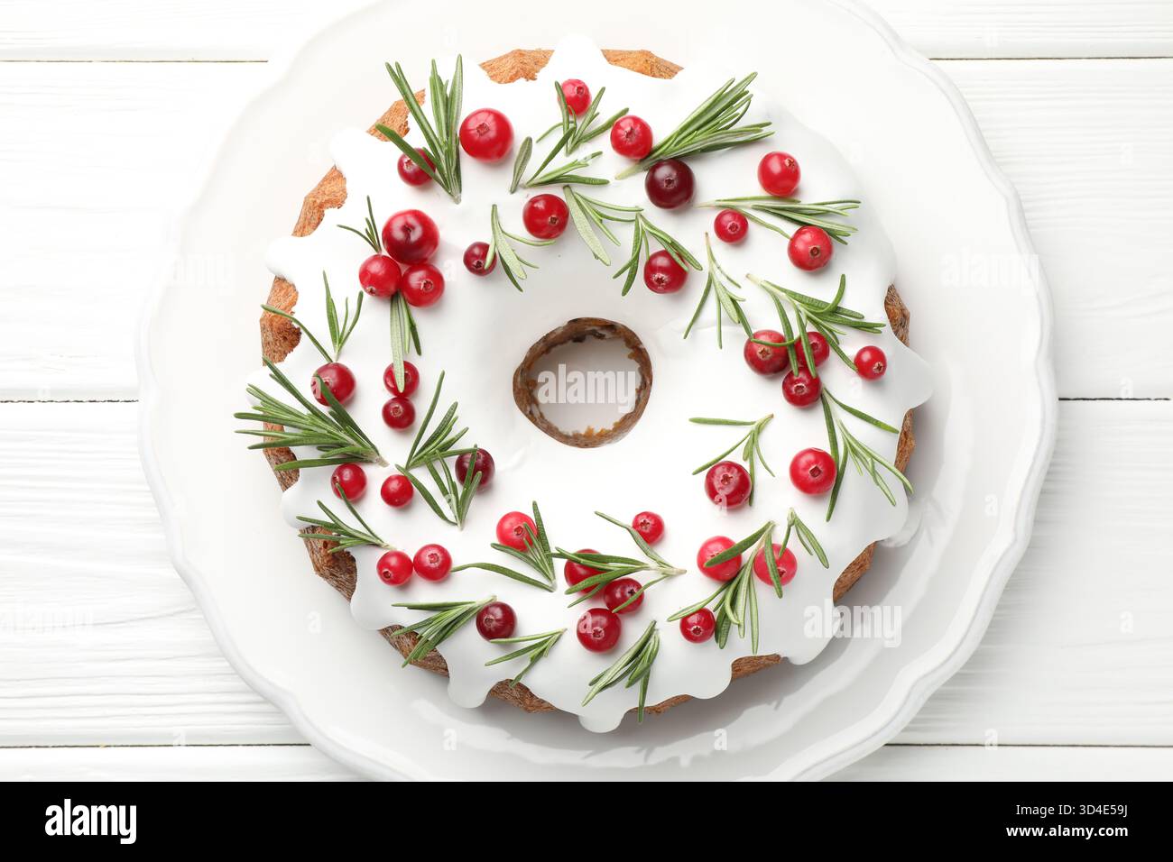 Tasty Christmas cake with icing, cranberries and rosemary on white ...