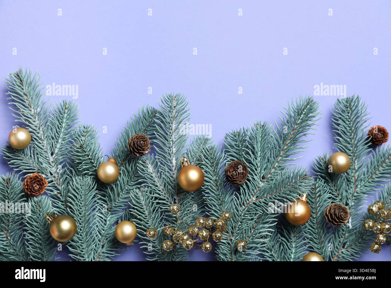 Christmas tree branches with festive decor on light purple background ...