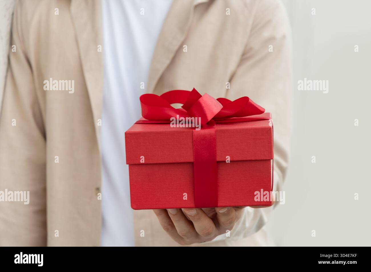 Red gift box with bow-knot in mans hand. Present with love for Birthday ...
