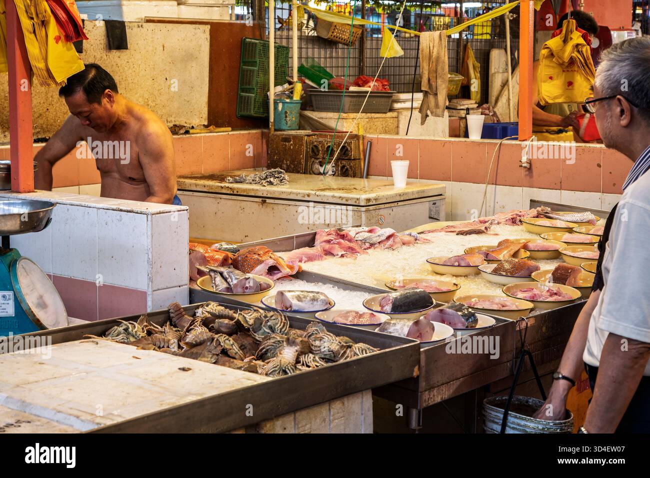 Fishmonger preparing fish behind stall of fish for sale at indoor fish ...