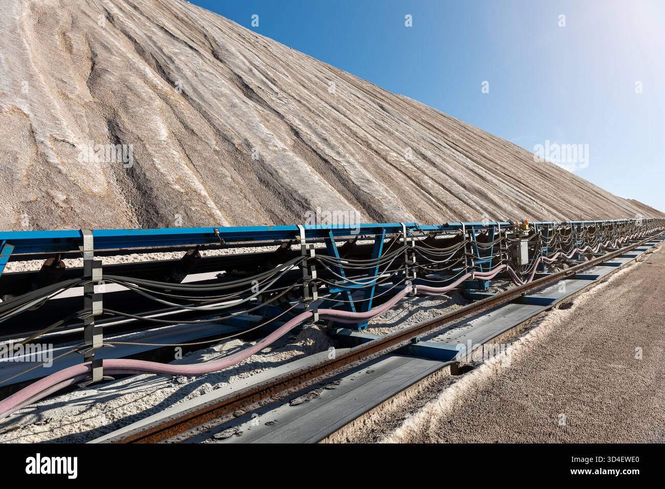 Long blue conveyor belt transports white potash ore material toward ...