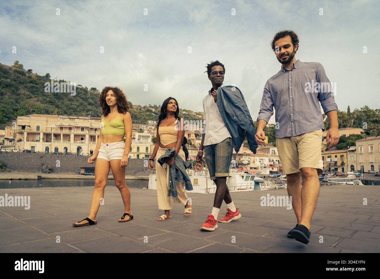 Four friends stroll along the waterfront in a charming coastal town ...