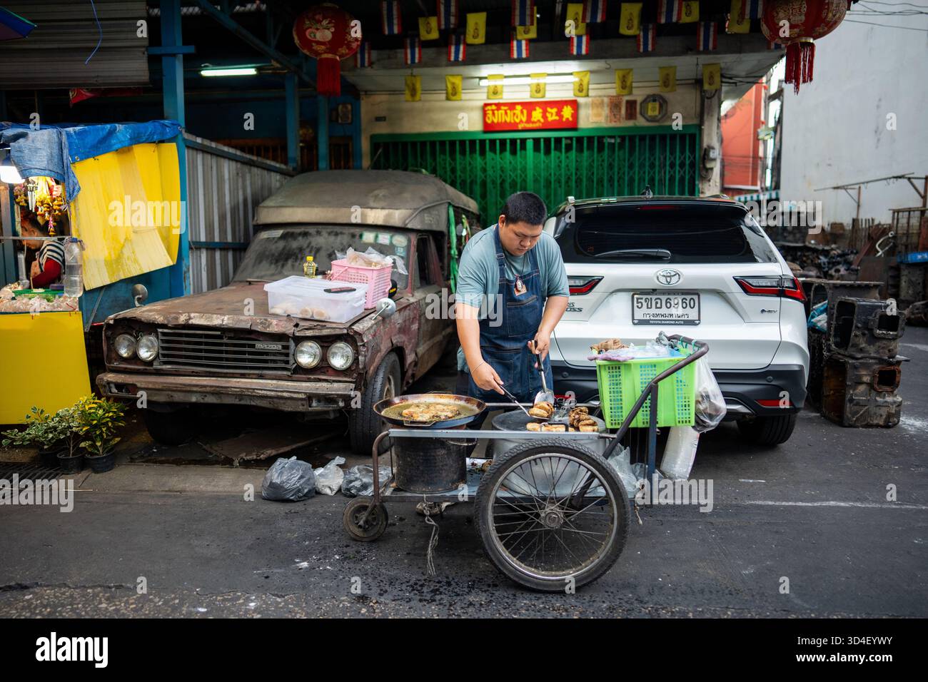 Young man vendor cooking junk unhealthy food on mobile cart outdoors at ...