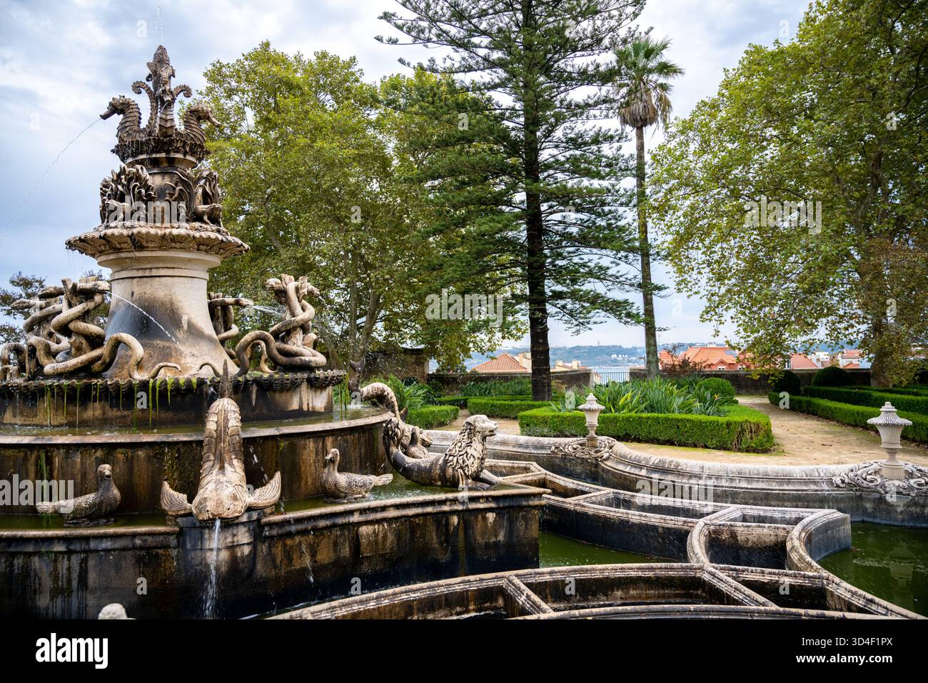 A fountain with sculpted figures stands in a garden pond area with ...