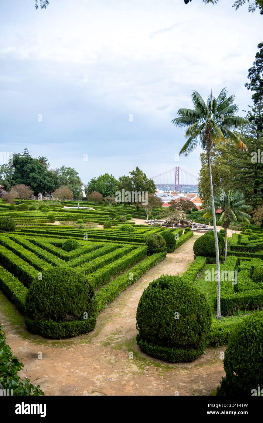 City rooftops above a formal hedge garden with the 25 de Abril Bridge ...