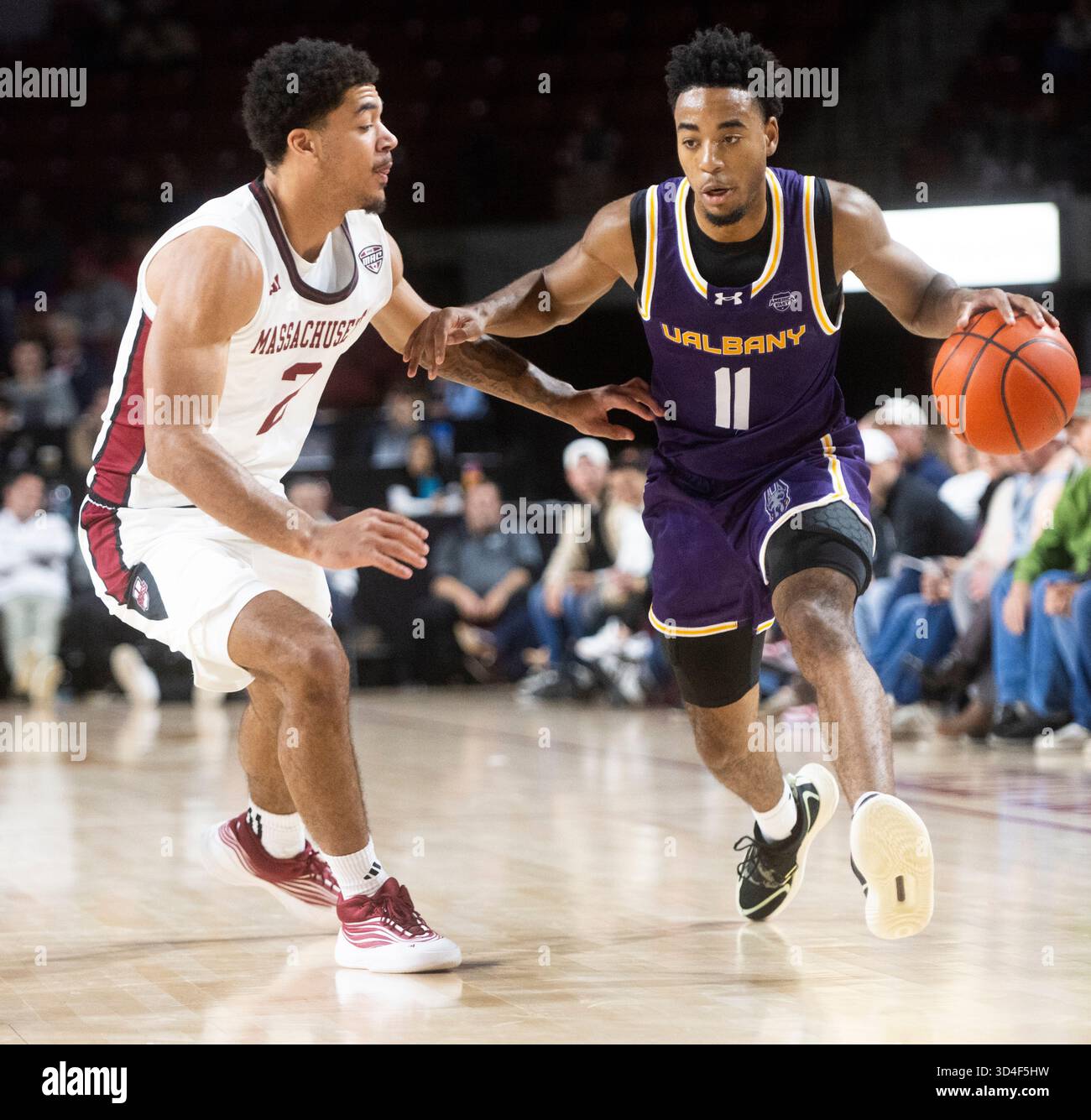 Albany guard Jaden Kempson (11) dribbles around UMass forward Dwayne ...