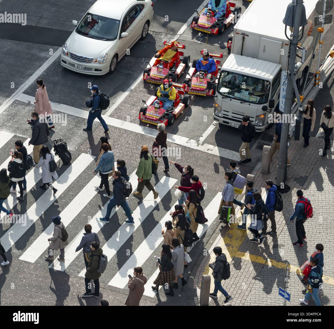 People cross zebra crossings, people in costumes ride small go-kart ...