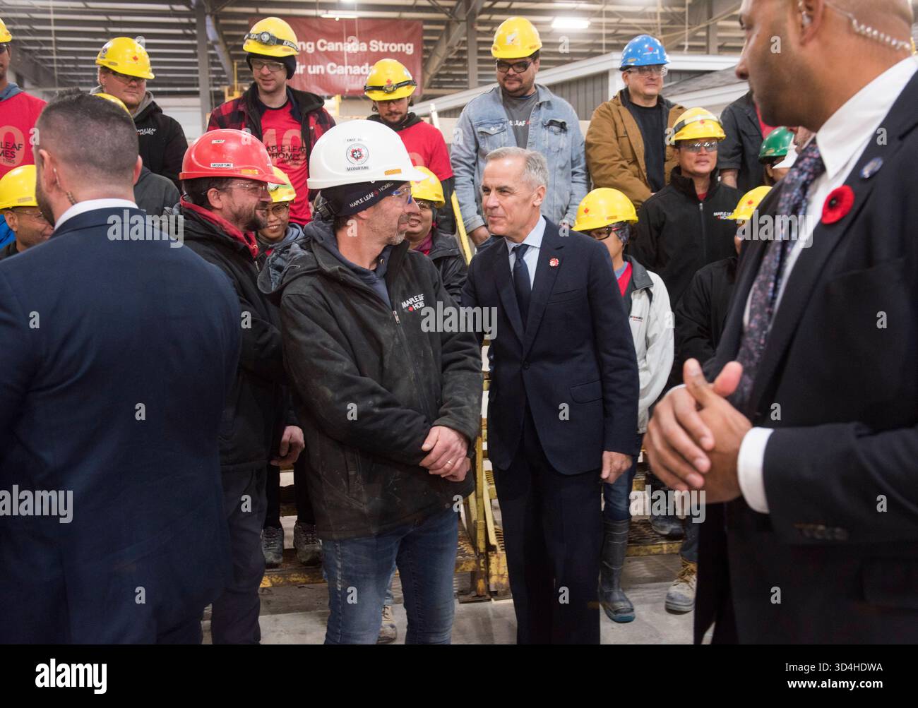 Prime Minister Mark Carney center, talks with workers after making an ...