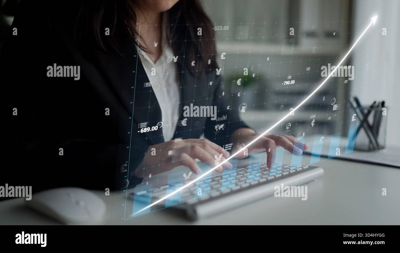 A business professional types on a keyboard with financial graphs and ...