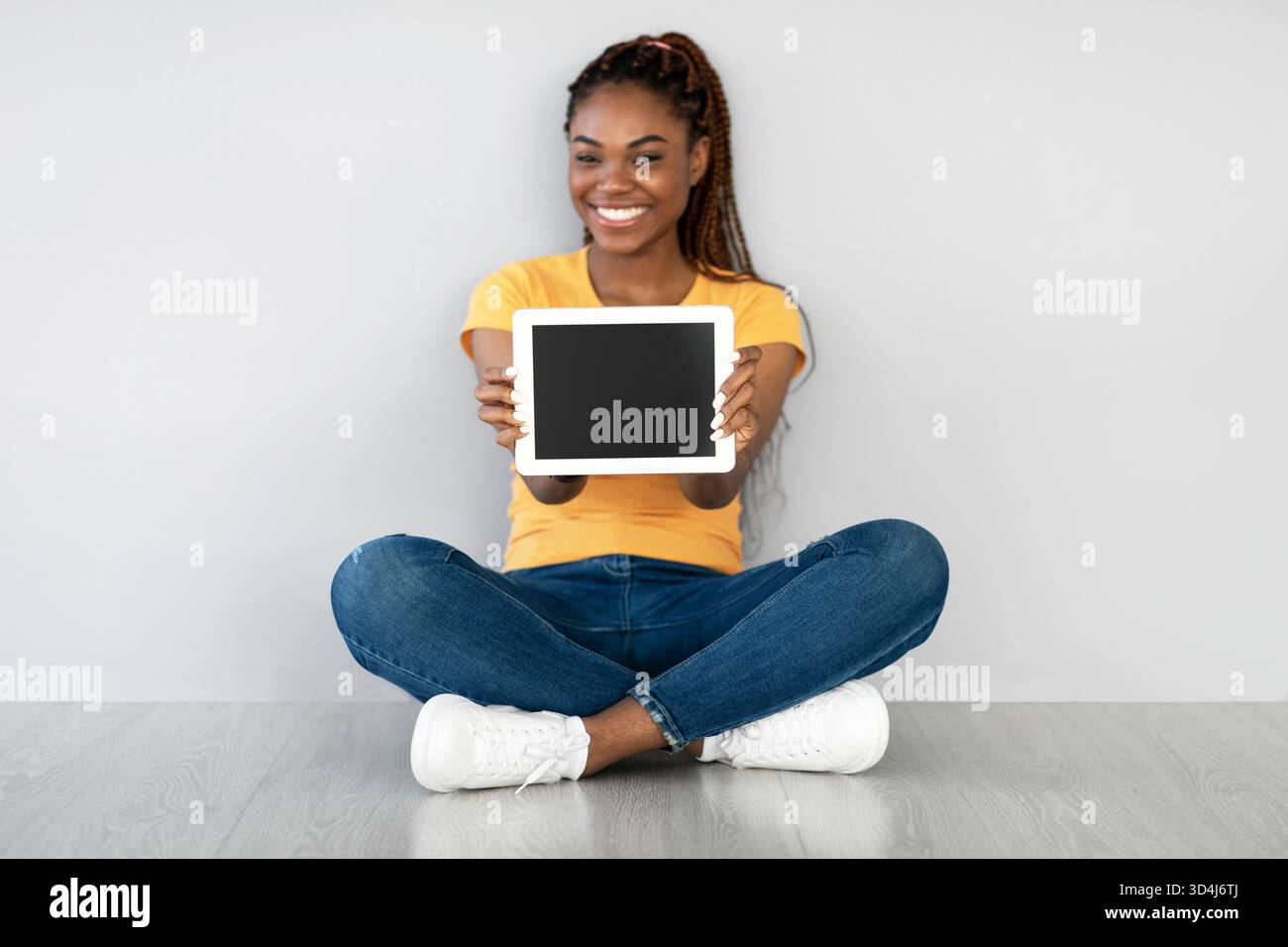 Beautiful Black Woman Sits on the Floor and Shows Tablet Computer ...