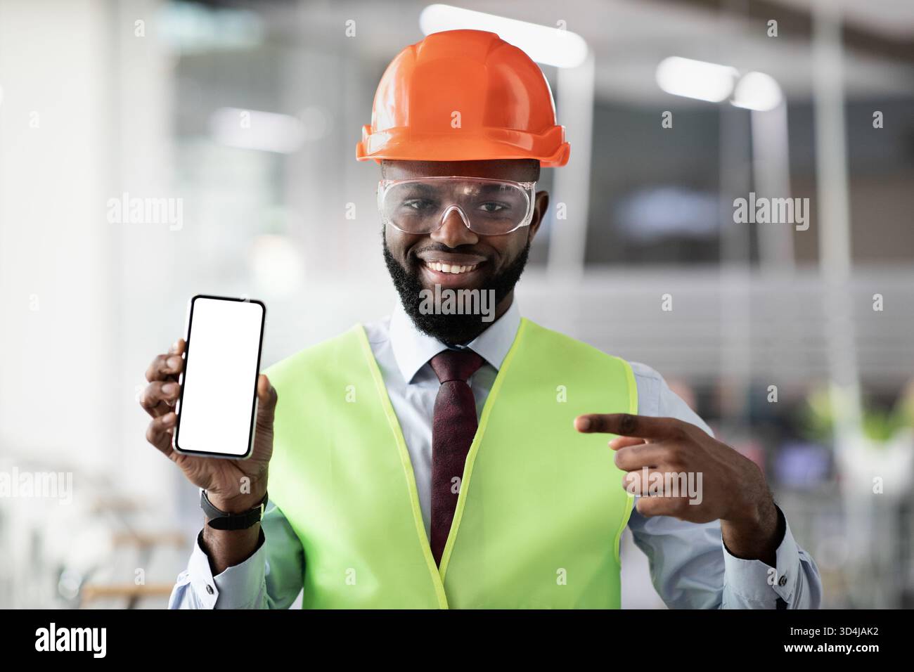 Happy african american architect pointing at smartphone with empty ...