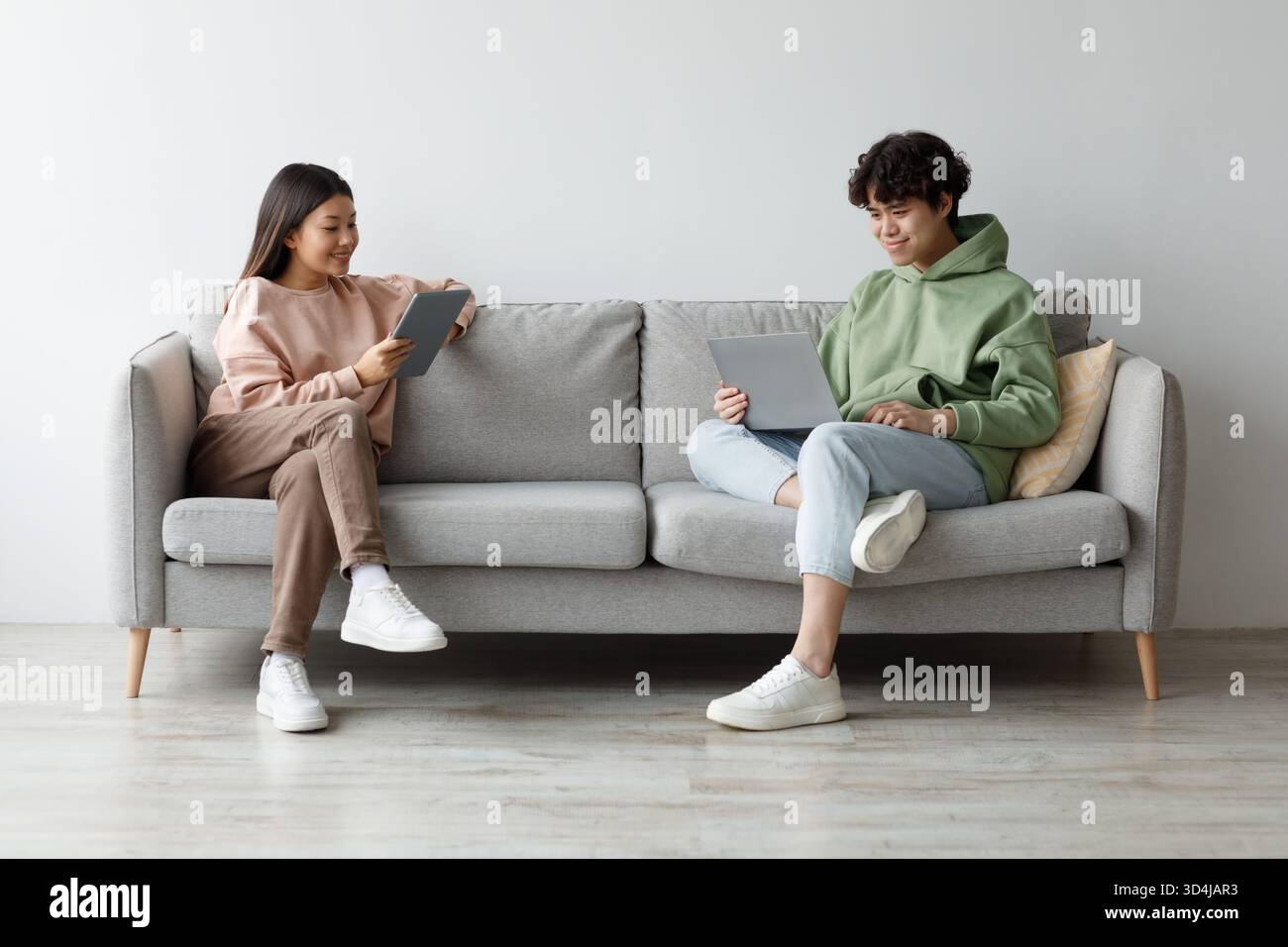 Young Couple Enjoying Tech Devices at Home on a Cozy Couch Stock Photo ...