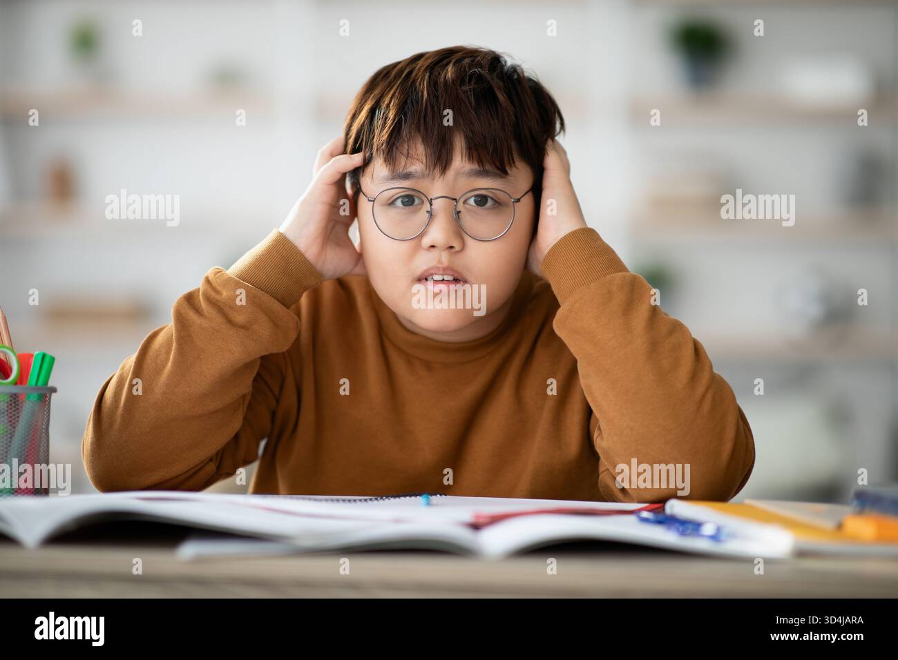 Stressed Teenager Struggling With Homework While Sitting at a Table in ...