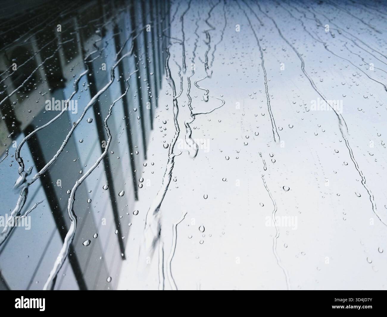 Rain drops on the window glass with skyscraper wall on the background ...