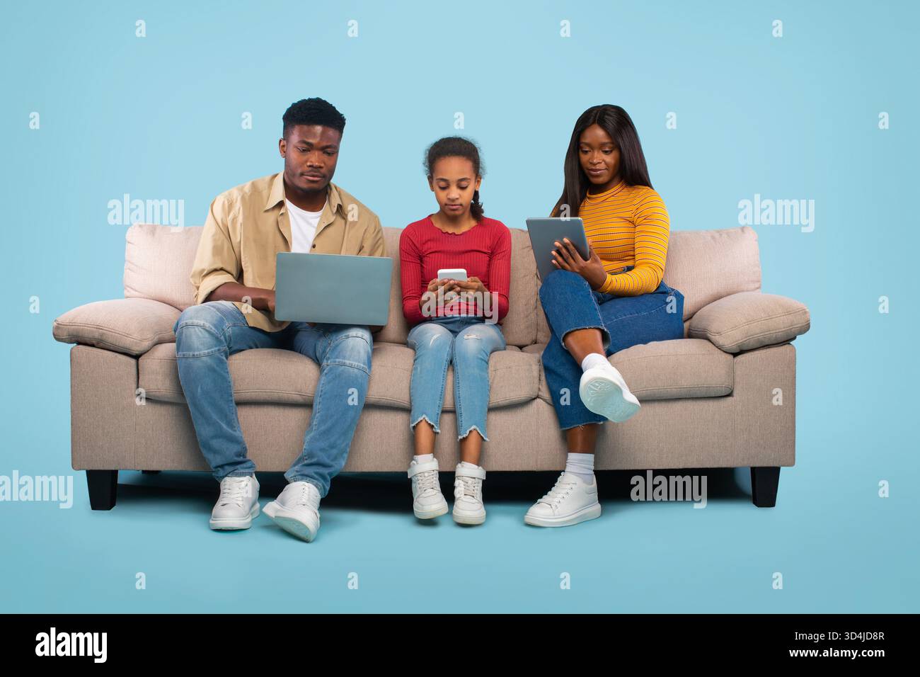Family Relaxing Together on a Couch While Using Electronic Devices in a ...