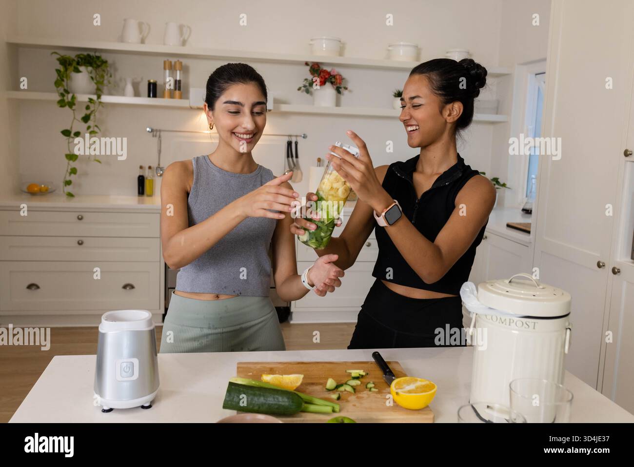 Blending diverse female friends mixing fruits and greens in white ...