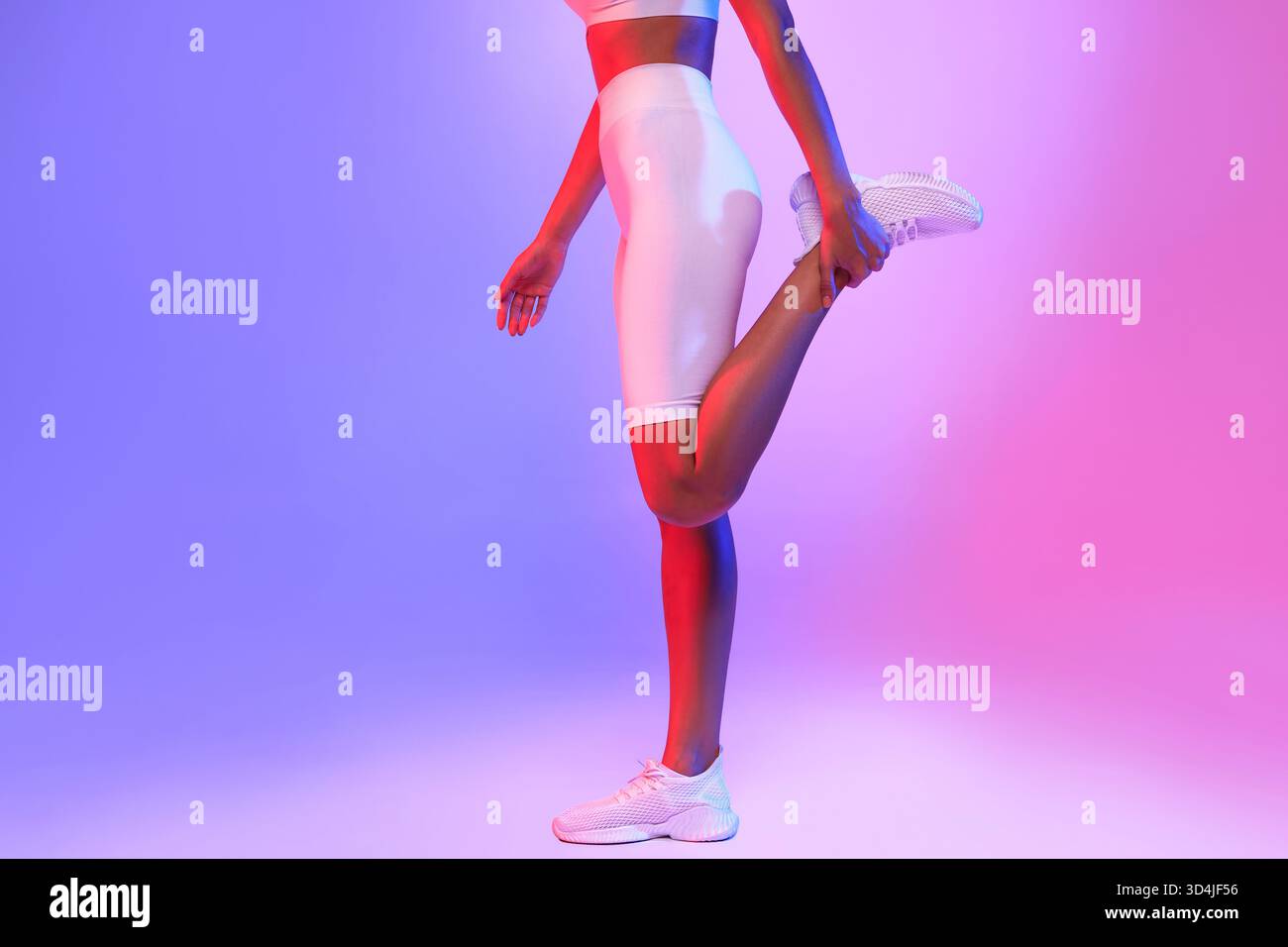 Sporty Female Warming up and Stretching Leg Over Vibrant Neon ...