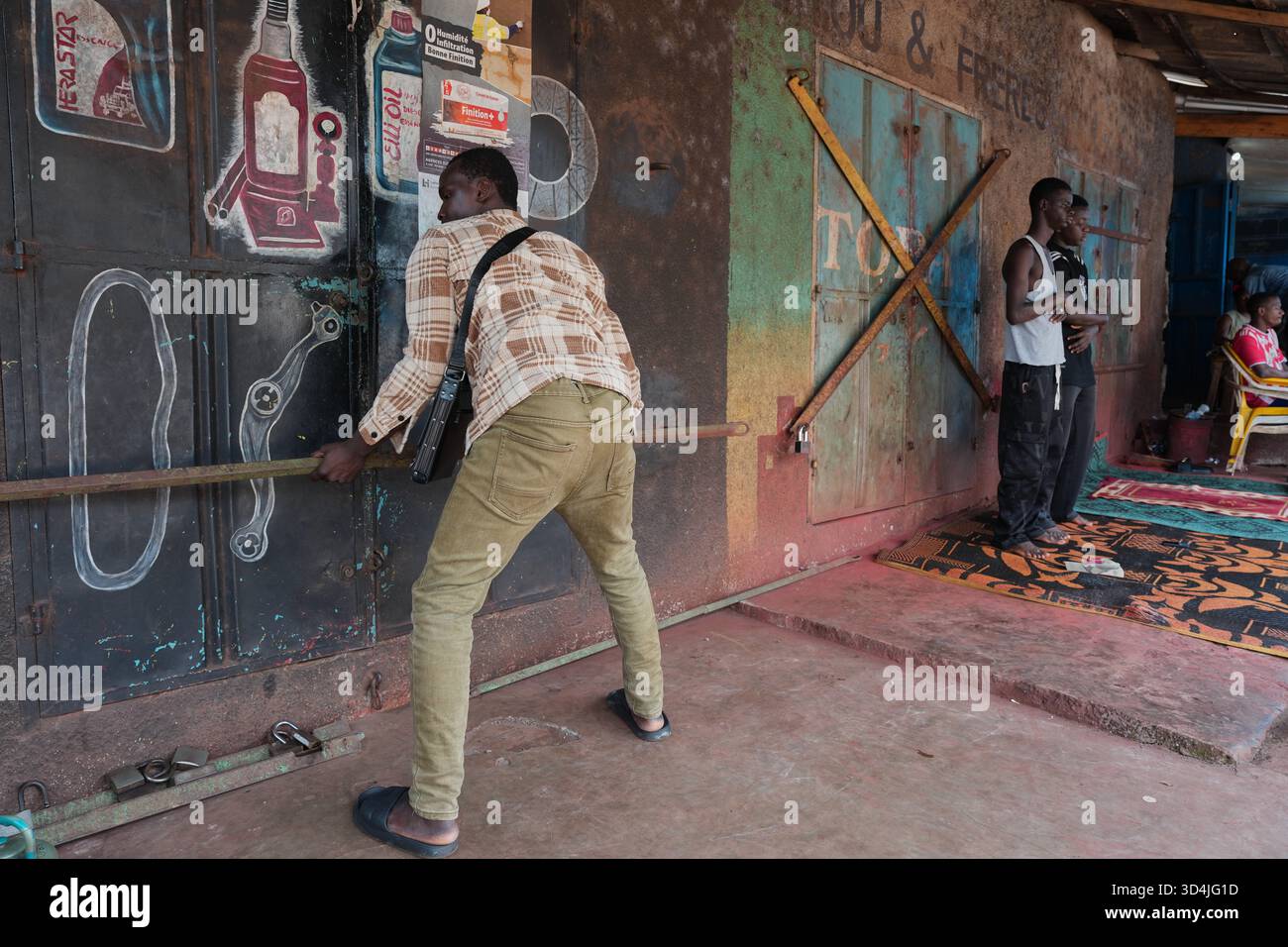 Oumar Bella Diallo, a returnee, opens the door of an auto repair shop ...
