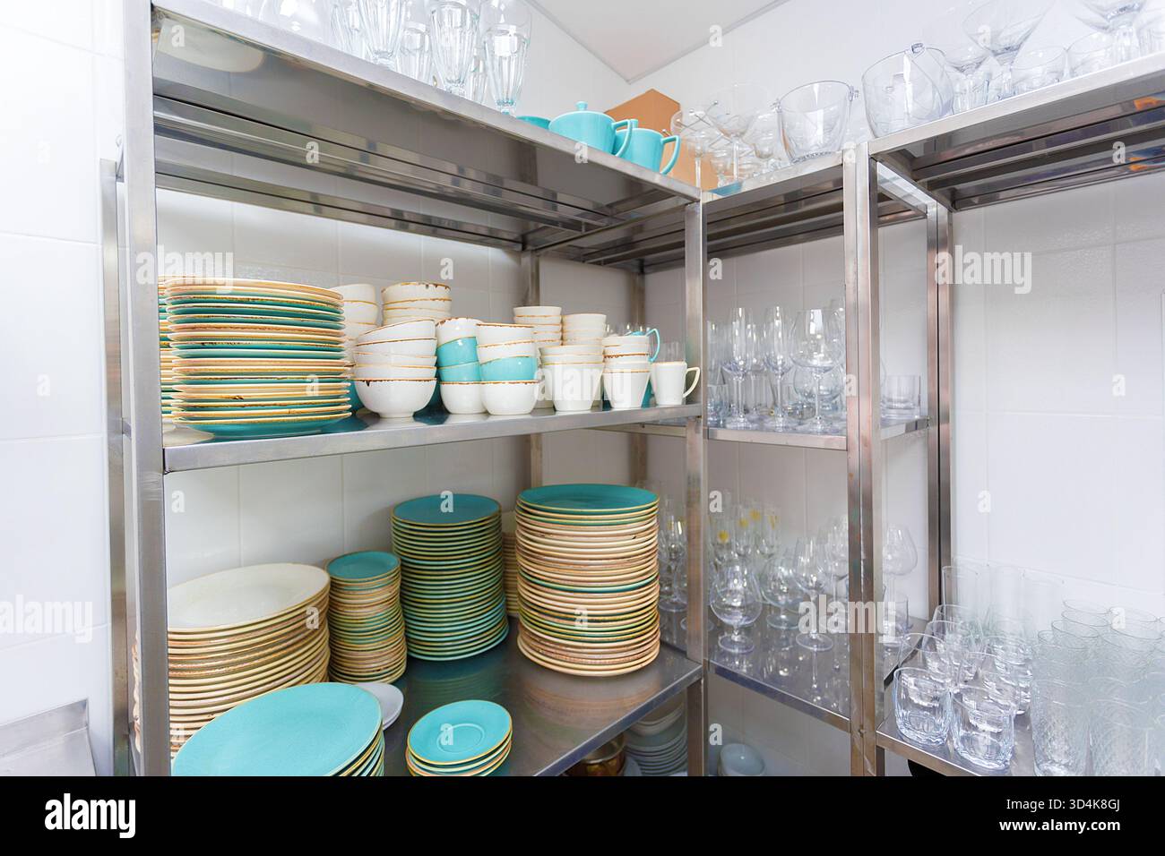 Shelves filled with neatly arranged dishes and glassware in a kitchen ...