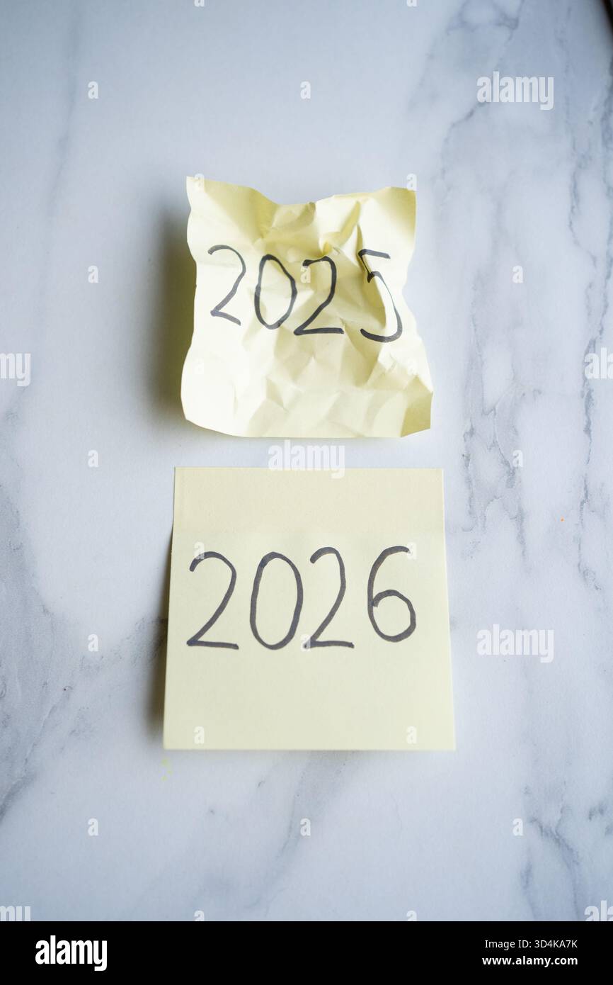 Crumpled 2025 sticky note above a flat 2026 sticky note on a white marble surface Stock Photo ...
