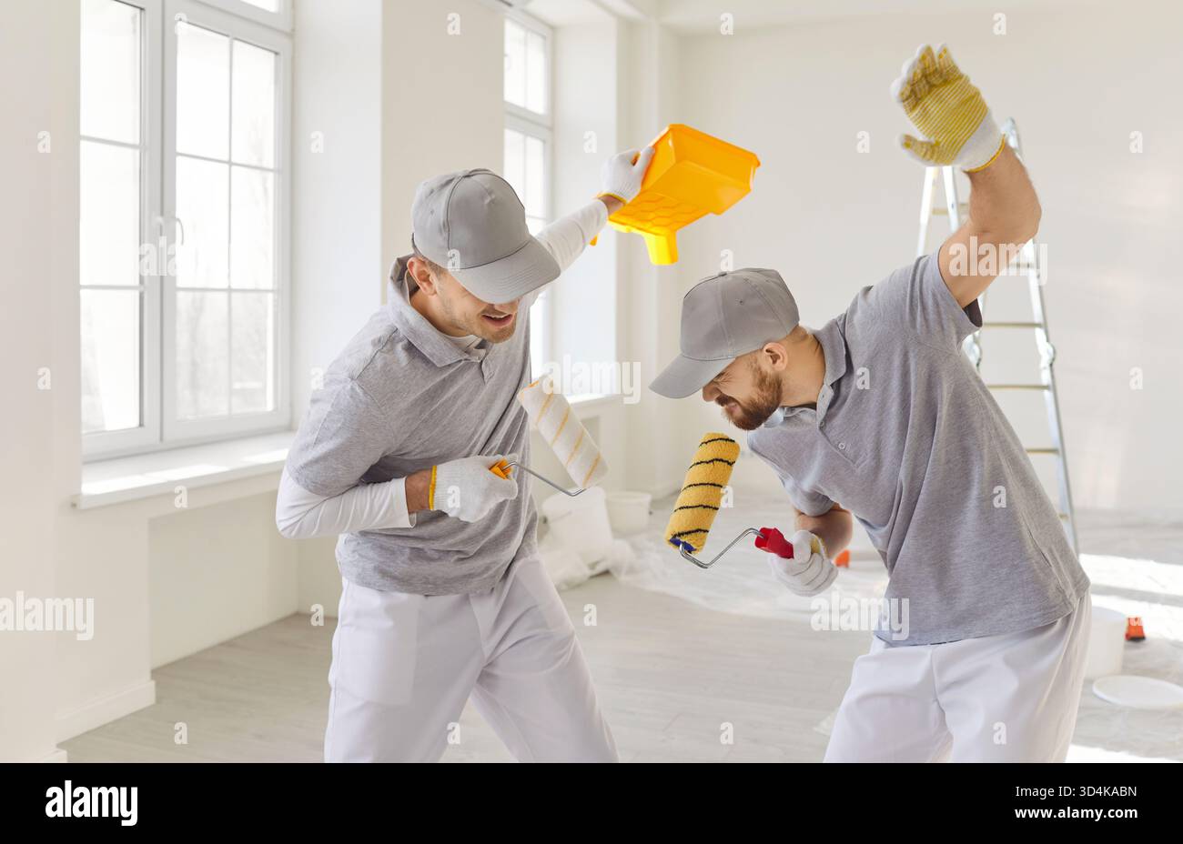 Two cheerful painters using paint rollers as microphones, having fun ...