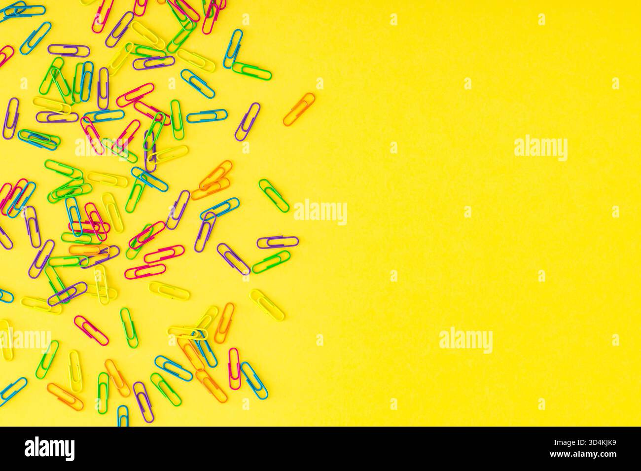 Colorful paper clips on yellow background. Office supplies and ...