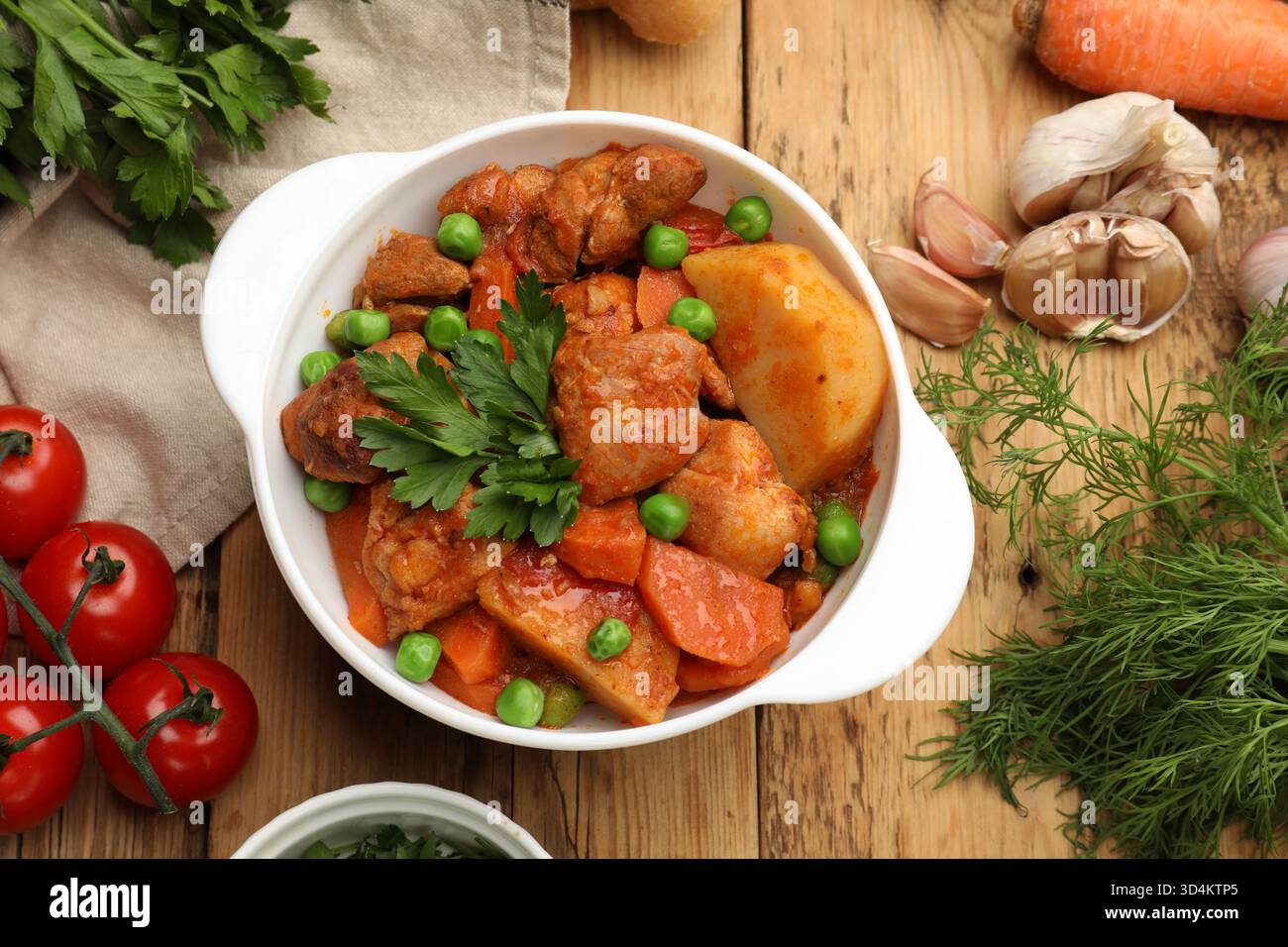 Delicious cooked stew in bowl and ingredients on wooden table, flat lay ...