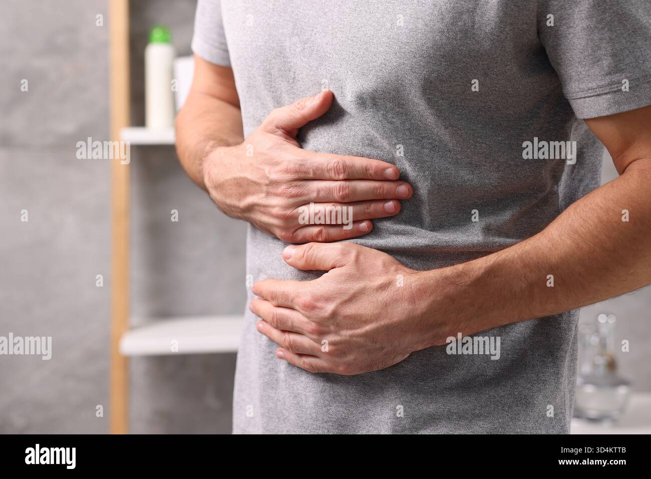 Man suffering from stomach ache and nausea in bathroom, closeup. Space ...