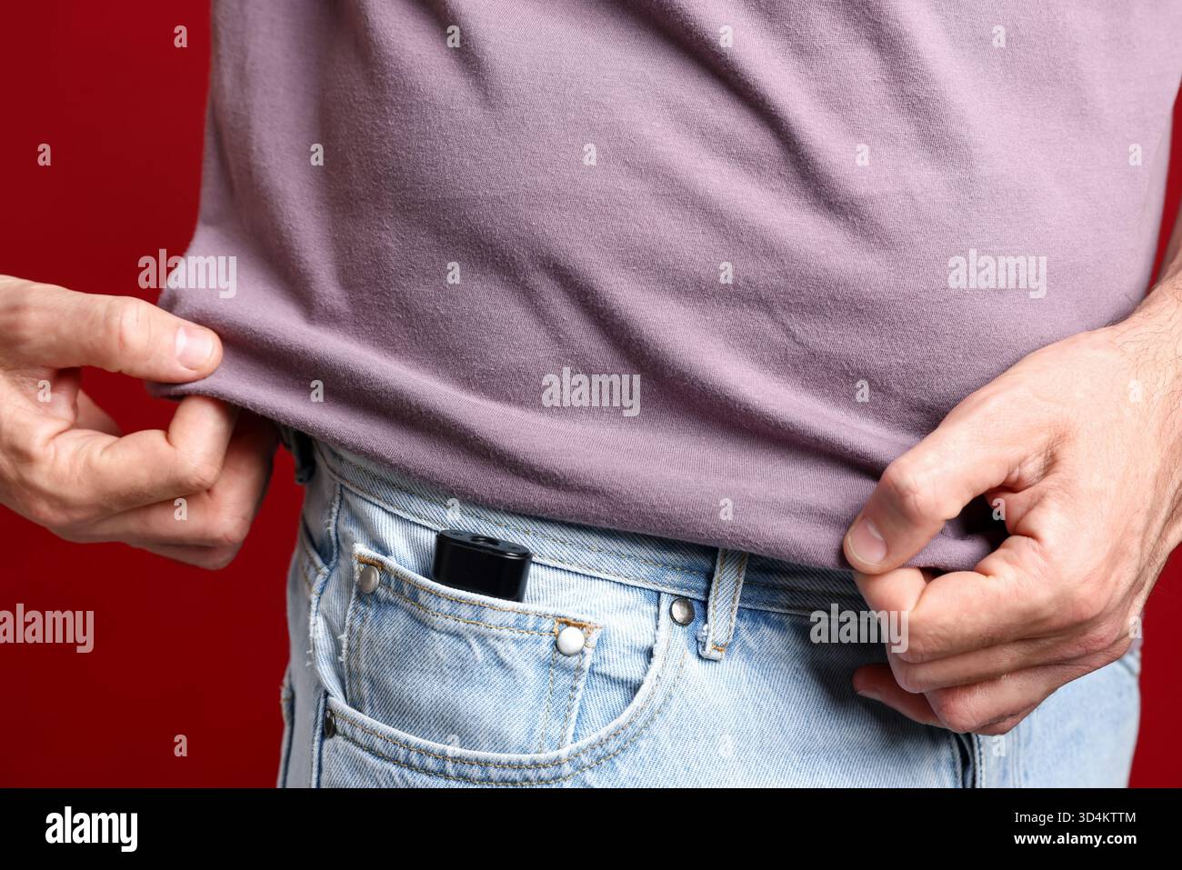Man with hidden spy camera in his pocket on red background, closeup ...