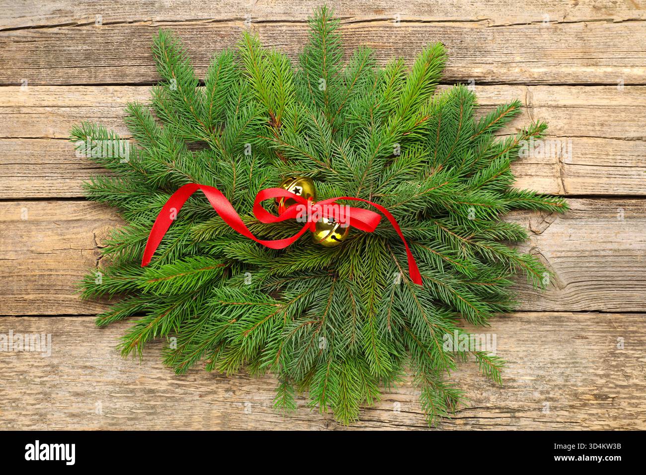 Christmas tree branches, jingle bells and ribbon on wooden table, top ...