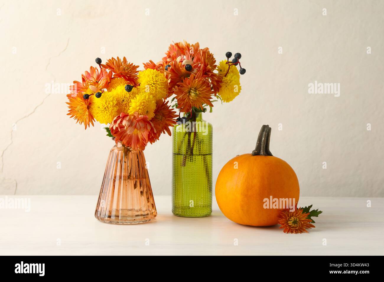 Autumn atmosphere. Vases with beautiful flowers, berries and pumpkin on ...