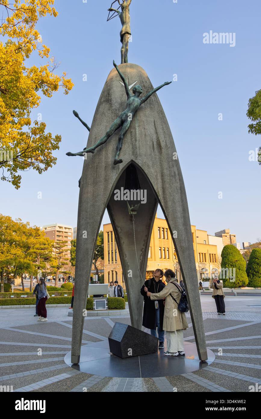 Hiroshima, Japan - March 20, 2025: Two woman ring the bell of the Children's Peace Monument in ...