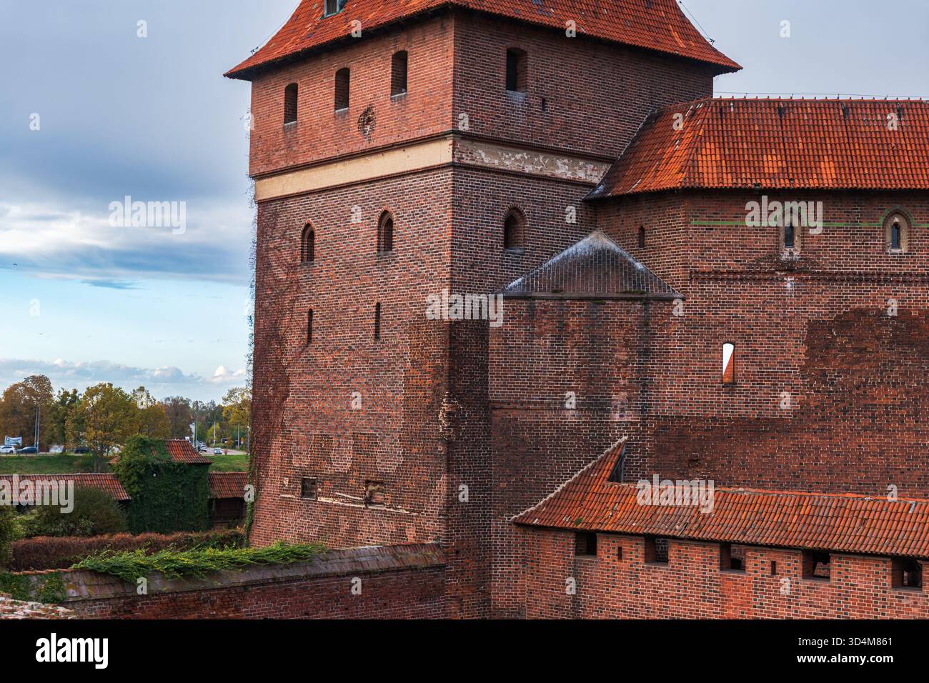 Red brick Gothic tower and walls with orange roofs stand in Malbork ...