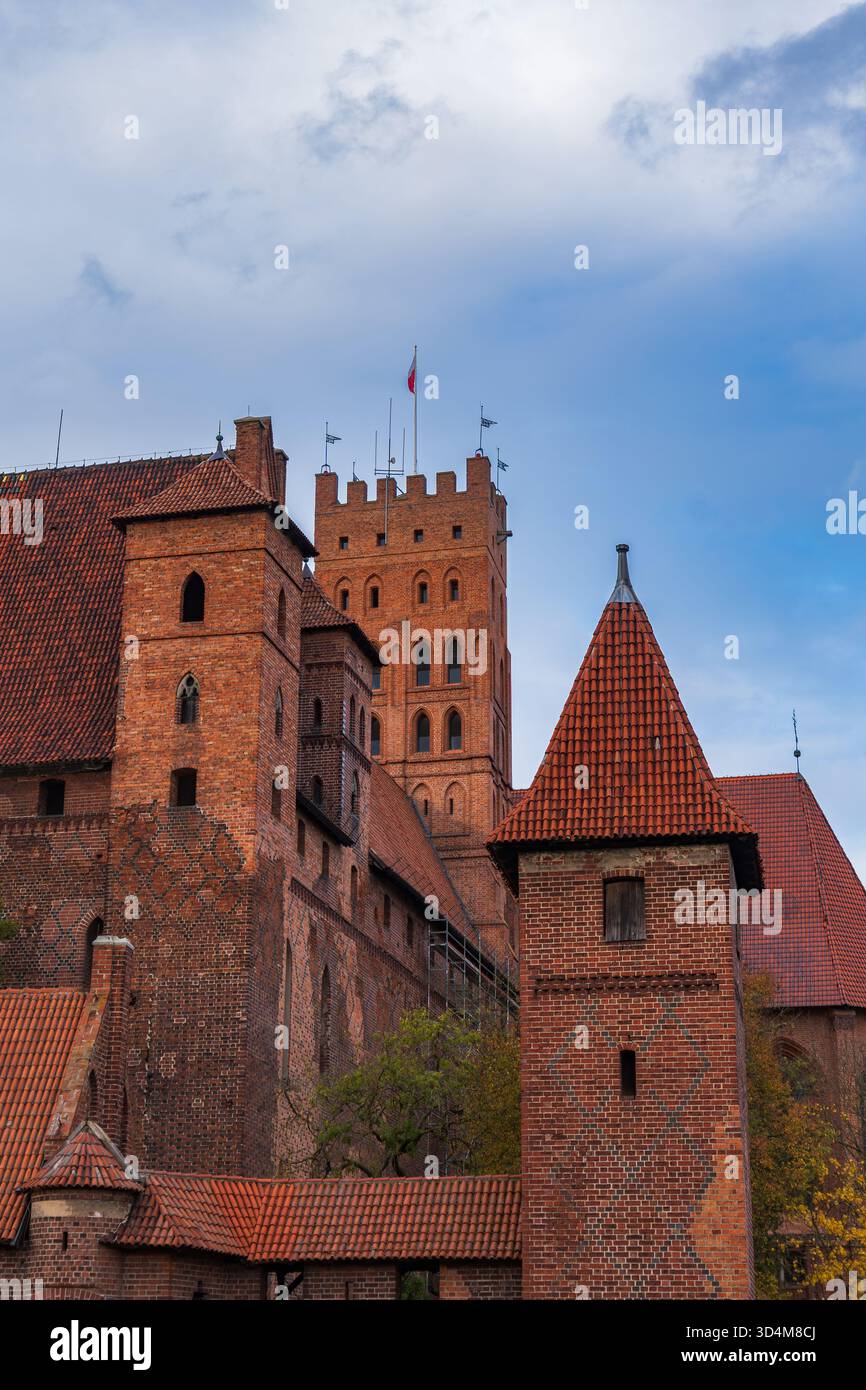 Red brick Malbork Castle in northern Poland shows keep, flags, and ...