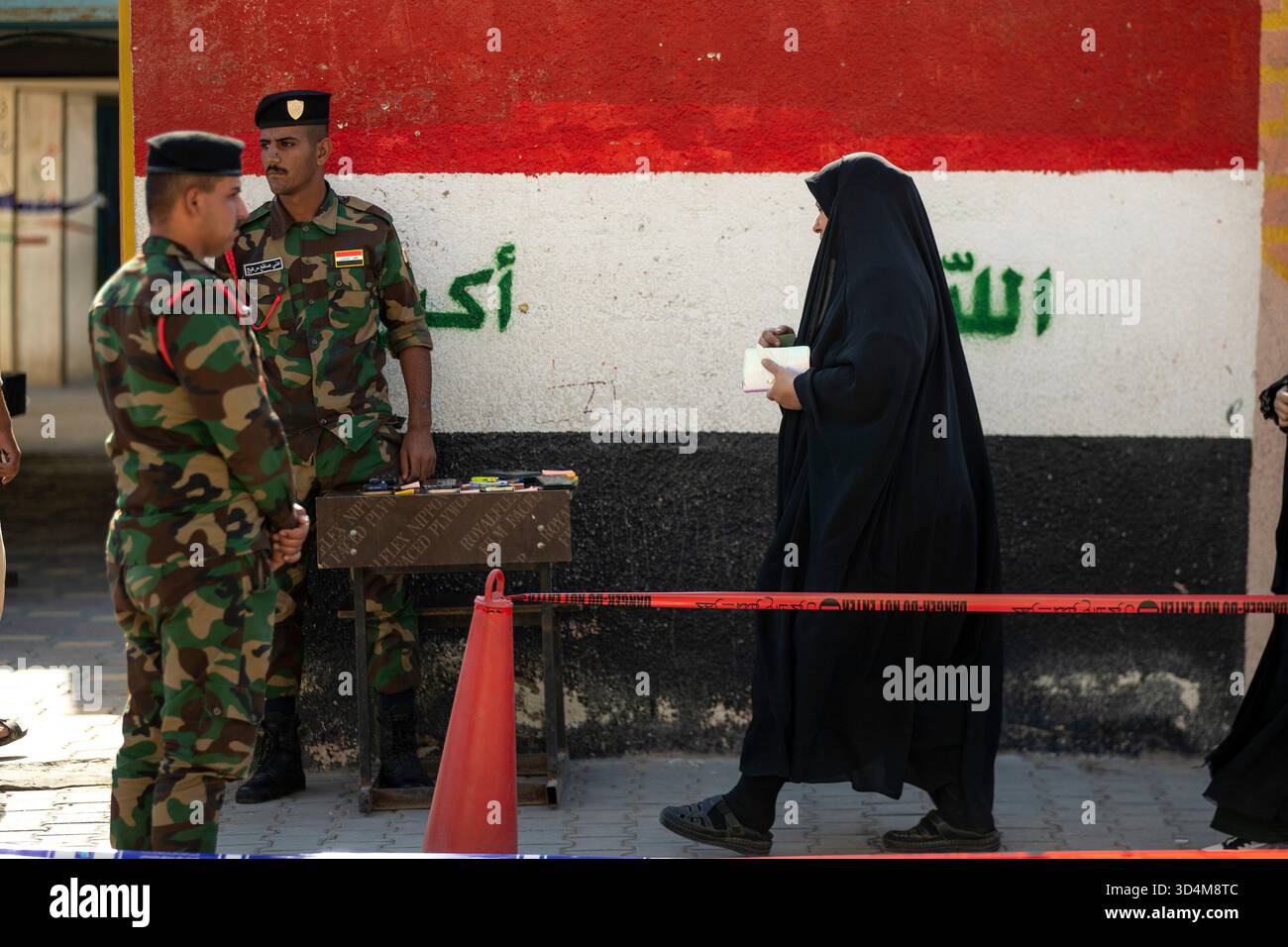 Iraqi police officers stand guard at a polling center as voters arrive ...