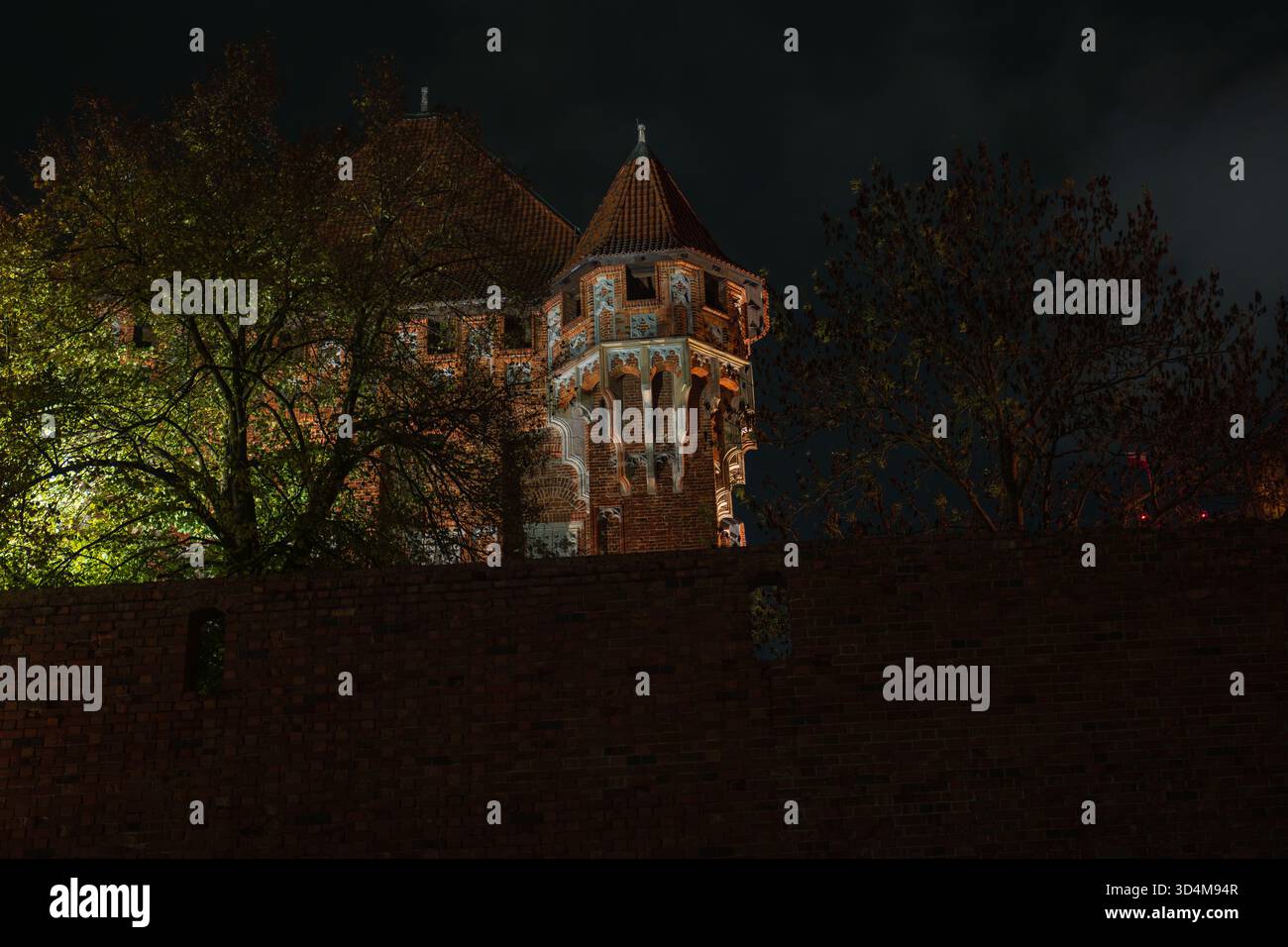 Malbork Castle in Poland shows a red brick Gothic tower and dark wall ...