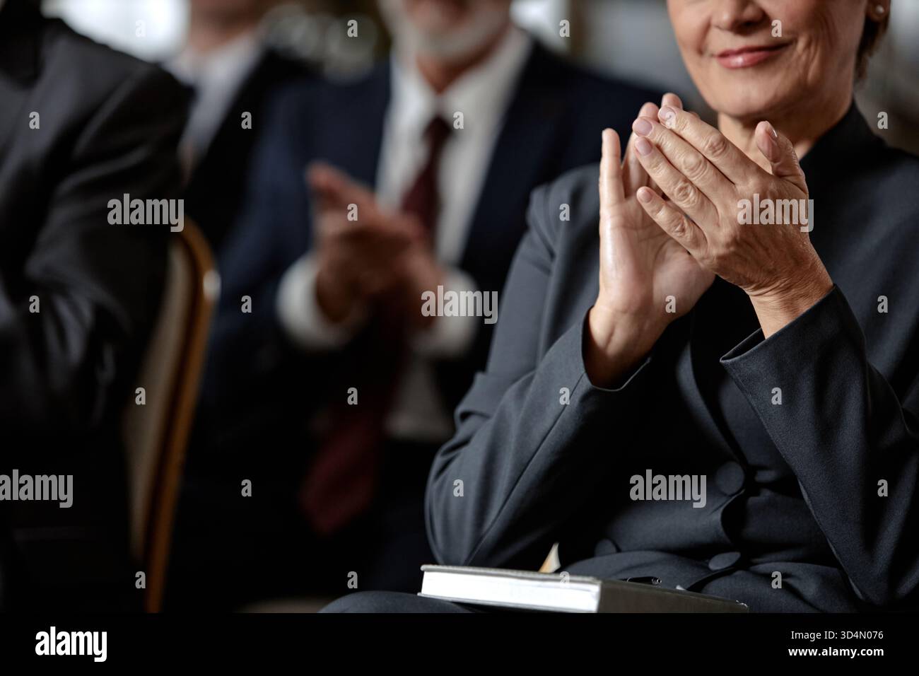 Middle aged Caucasian woman sitting in audience clapping hands during ...