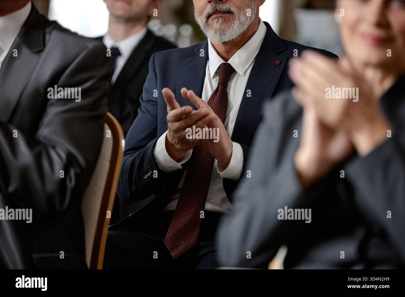 Middle aged Caucasian man in suit sitting among group of professionals ...