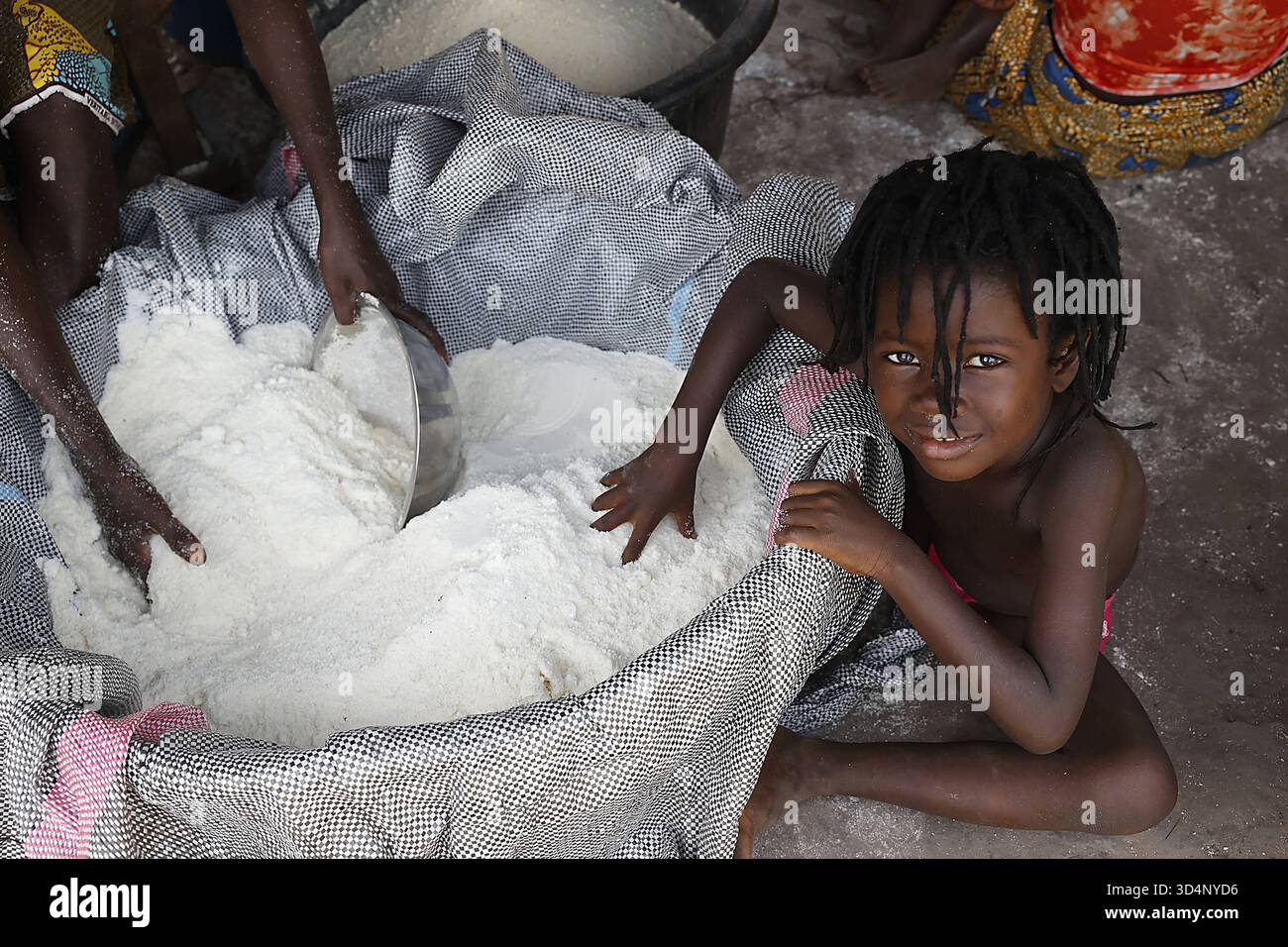 Child sitting in a flour making workshop in Benin. Child sitting in a ...