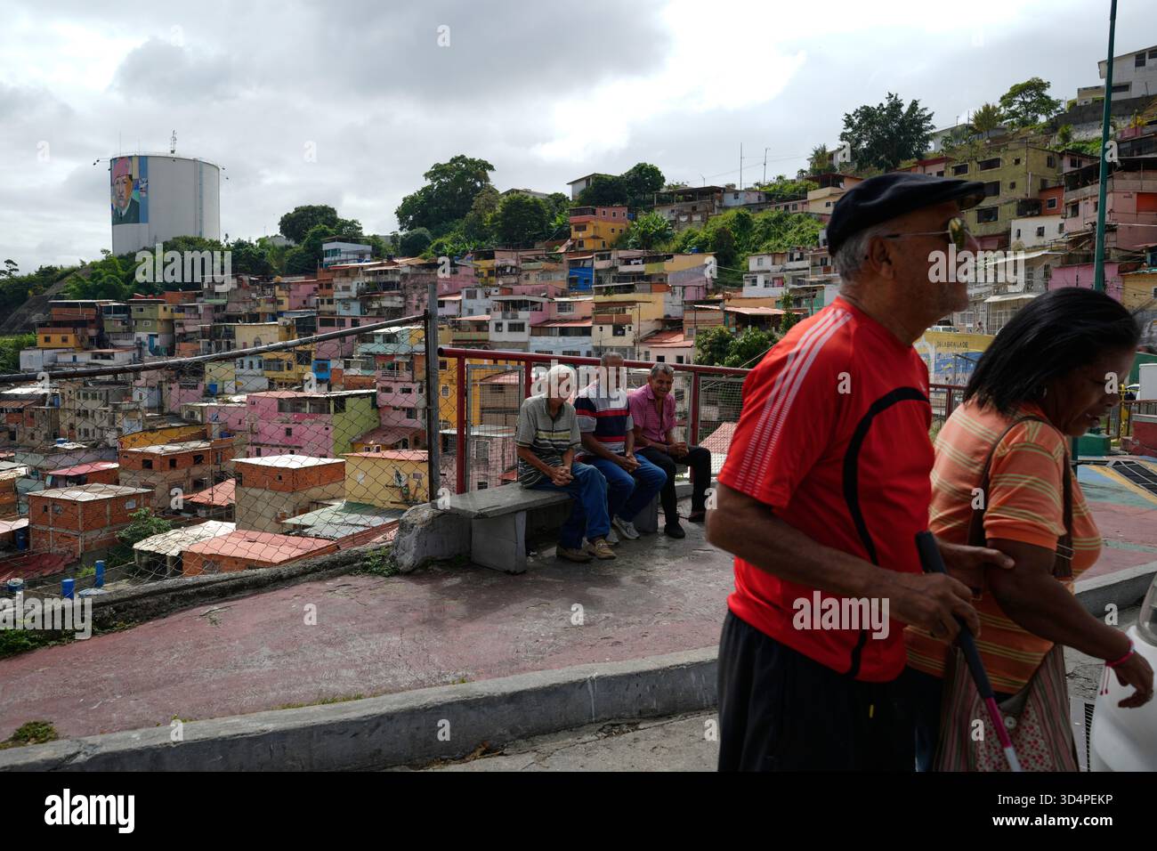A couple walks past as residents sit on a bench in the 23 de Enero ...