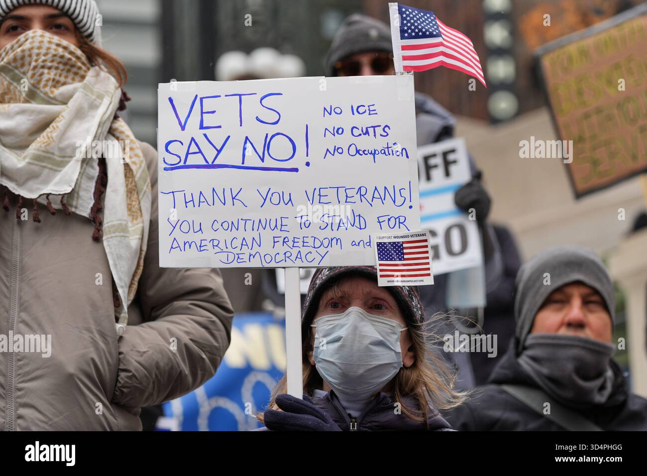 Maureen Harazin holds a sign and a flag during a Veterans Day protest ...