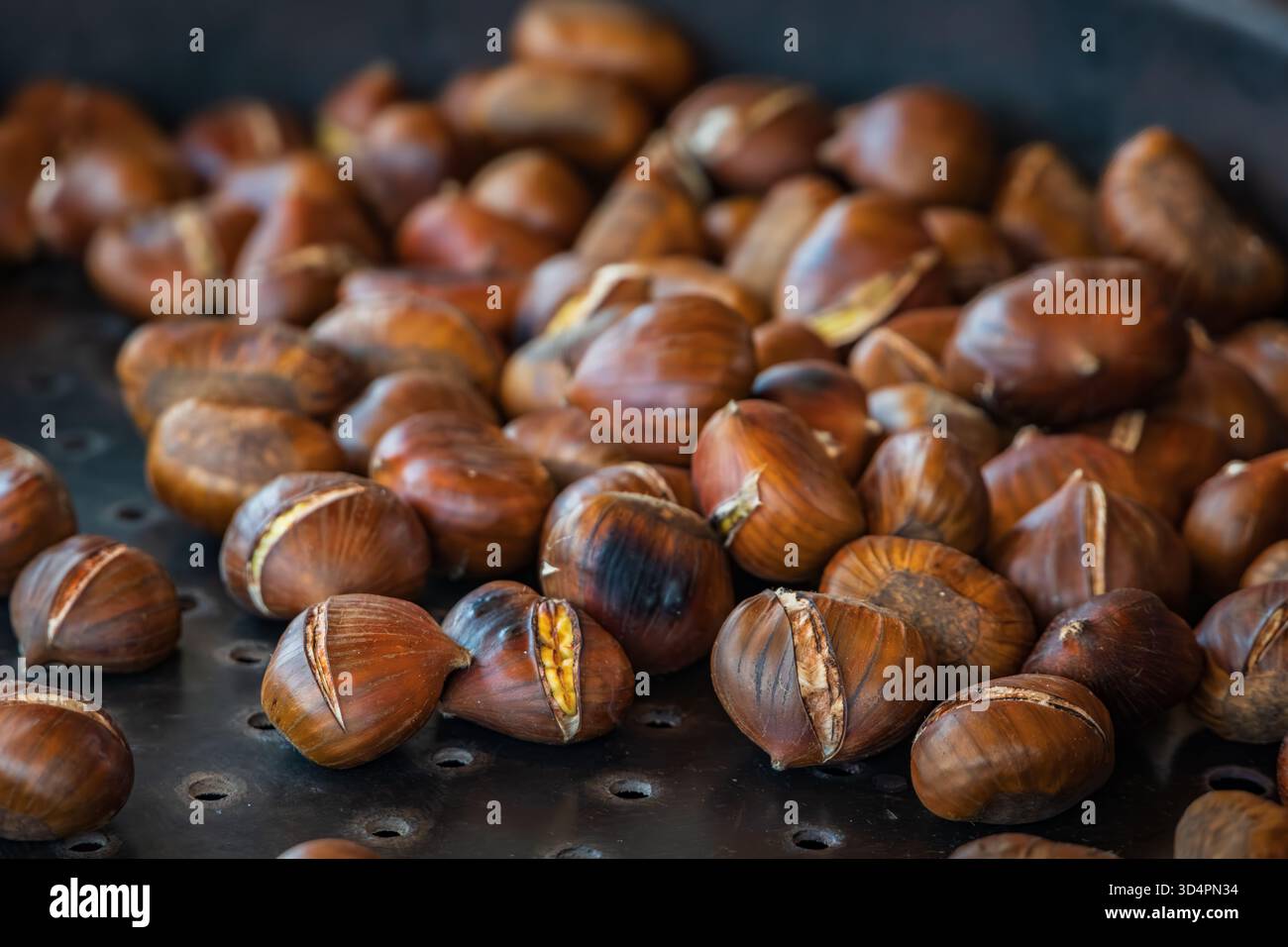 Traditional roasted chestnuts cook in a hot pan at a Christmas market ...