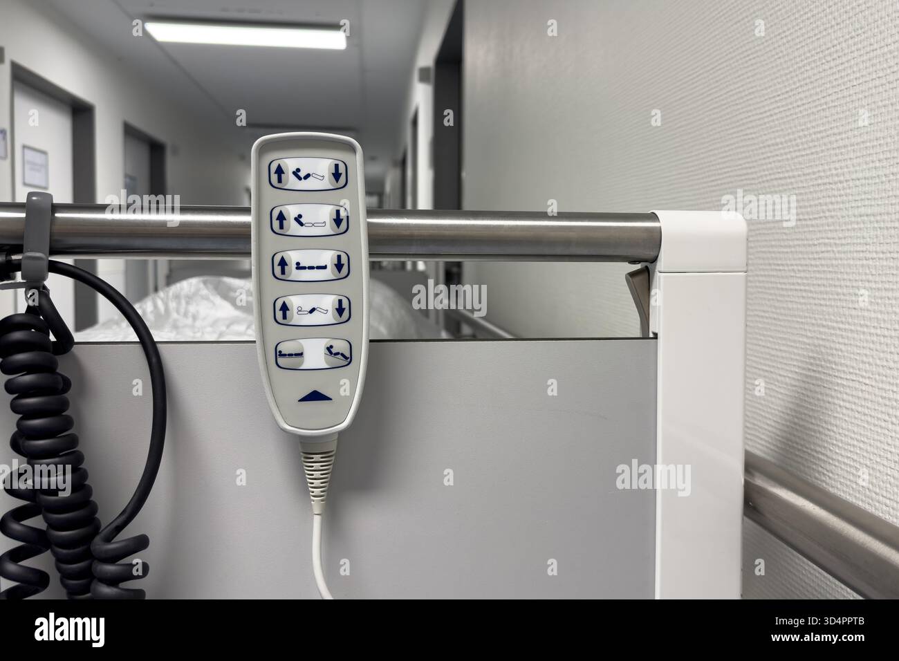 A control panel is seen mounted on a metal rail beside a hospital bed ...