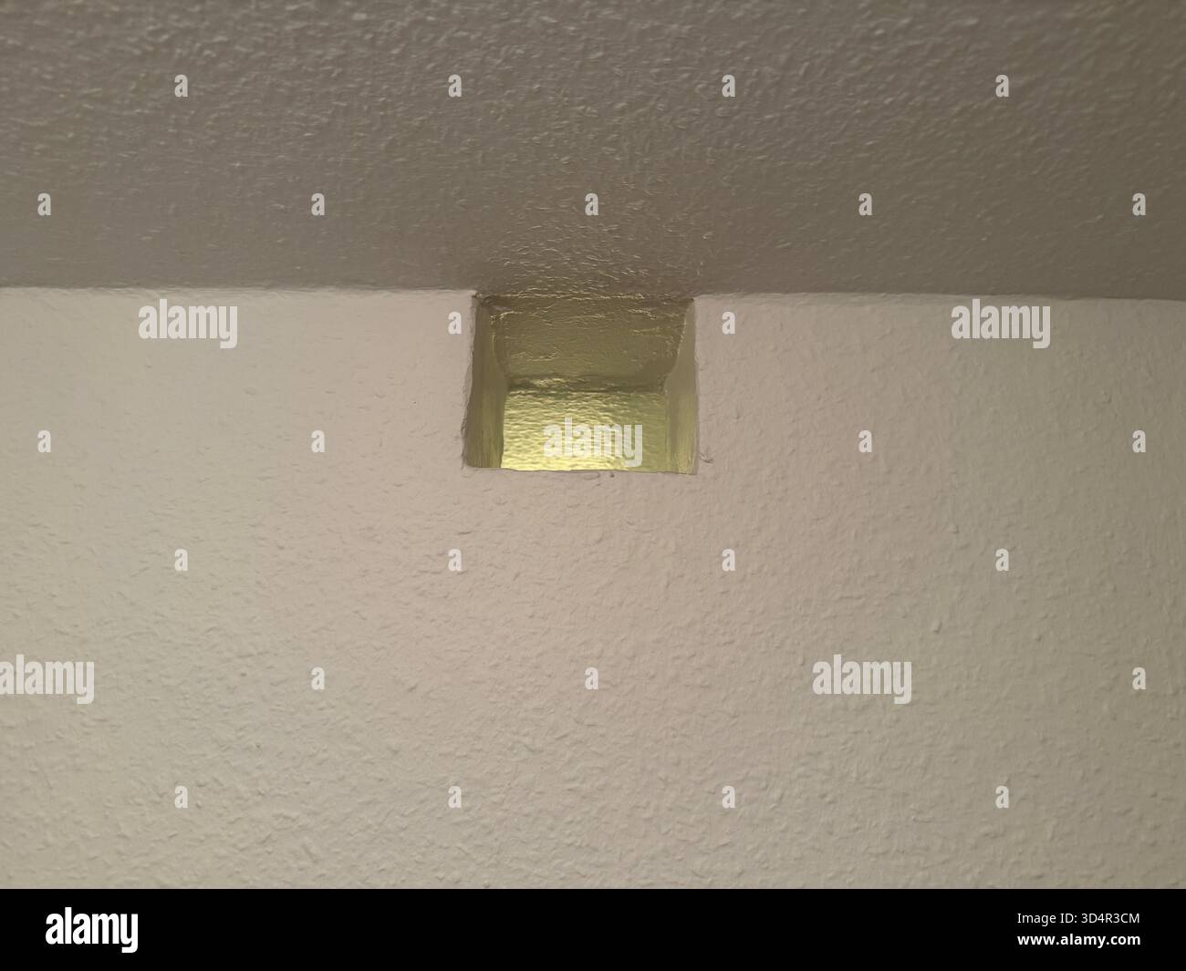 Minimalist wall detail showing a small ventilation opening with soft ...