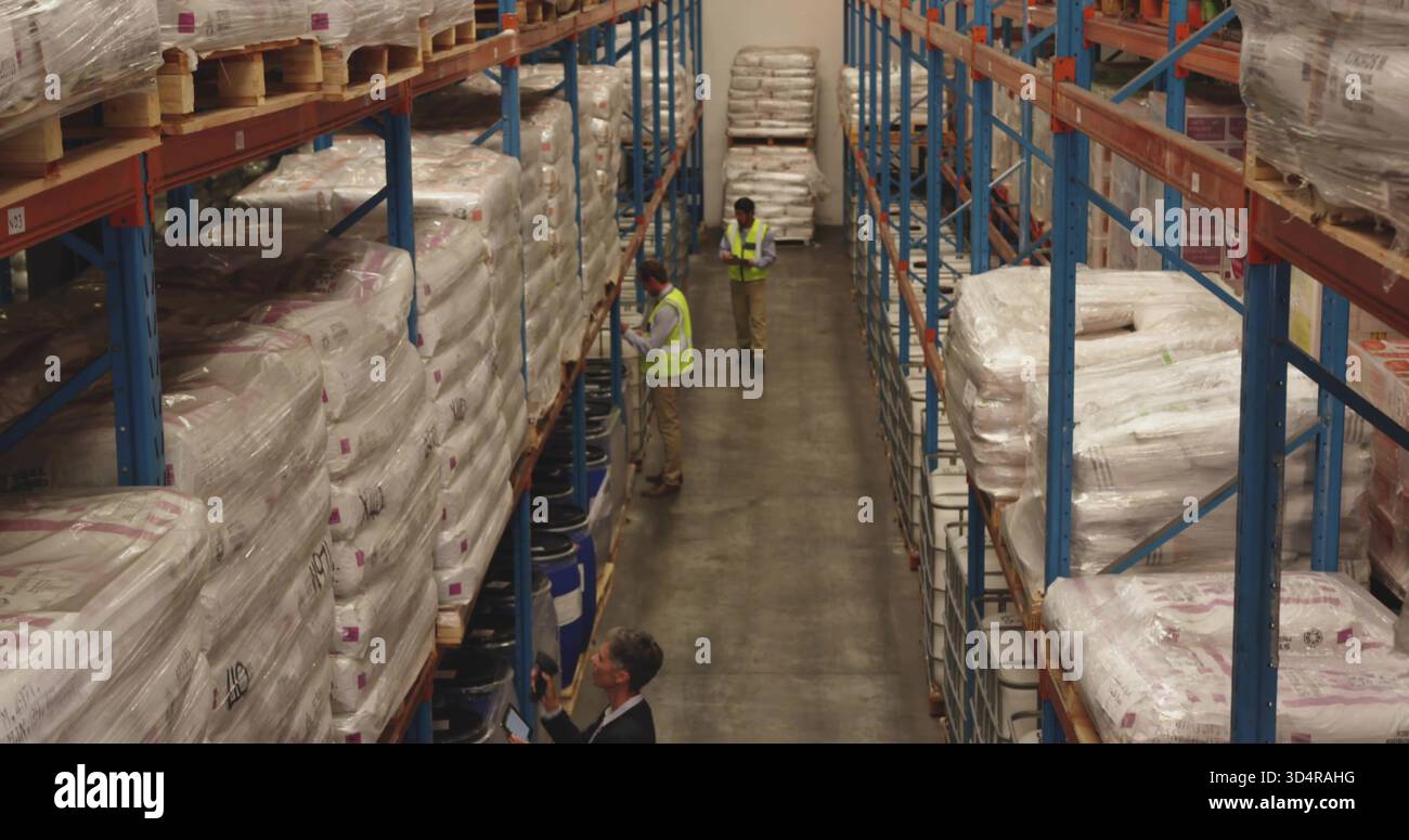 Inspecting dark-jacketed manager and hi-vis workers scanning shelves in ...